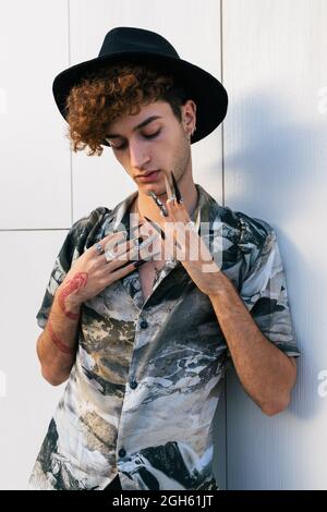 Young vain man in stylish wear standing on tiled walkway with eyes ...