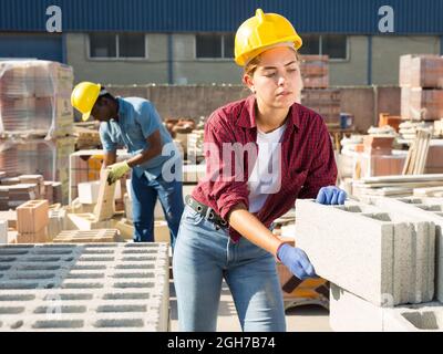Woman checking quality of bricks at construction store Stock Photo - Alamy