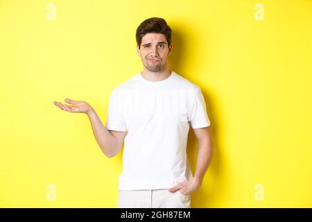 Confused and displeased guy raise hand, grimacing puzzled, standing ...