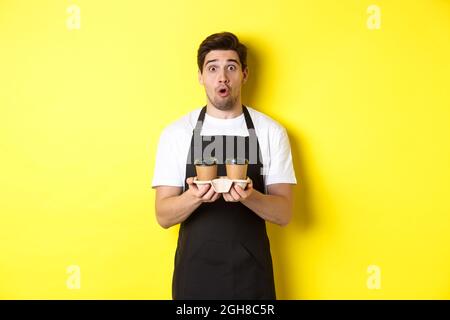 Barista serving coffee, looking surprised at camera, wearing black ...