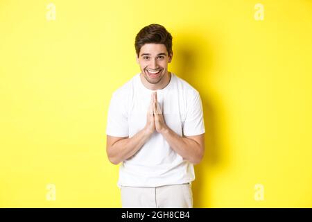 Handsome guy saying thank you, bowing and holding hands in namaste ...