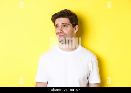 Skeptical and reluctant man looking displeased, pointing fingers up ...
