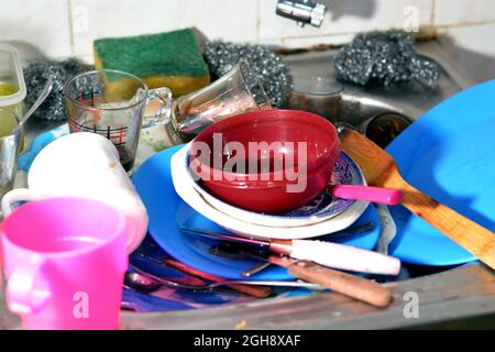 A dirty kitchen with used and unclean pots and pans on a greasy cooker ...