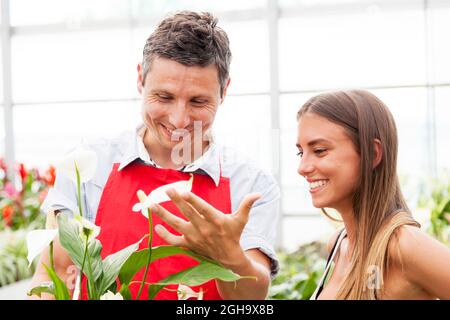 smiling salesman sells a plant to a pretty customer Stock Photo - Alamy