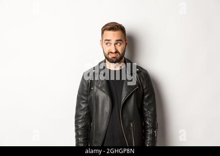 Indecisive gloomy man in black leather jacket, looking left and feeling ...