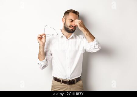 Tired businessman take-off glasses and rubbing eyes, standing exhausted ...