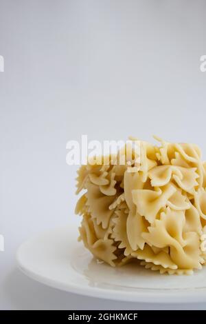 Cooked farfallini pasta in a shape of cube on a white plate. Copy space ...