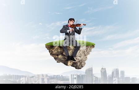 Young businessman with violin over the city Stock Photo - Alamy