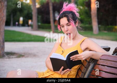 Surprised young woman reading book on white background Stock Photo - Alamy
