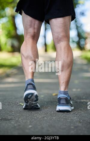 Closeup on the muscular calves and shoes of a marathon runner on an ...