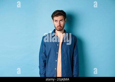 Sad man whining and sulking, looking up with upset face, standing on ...