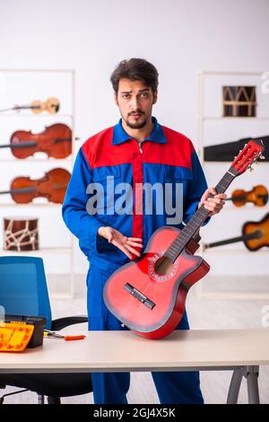Young repairman repairing musical instruments at workplace Stock Photo ...