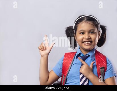Happy indian school girl pointing advertising isolated on violet ...