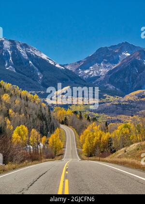 An empty Colorado Highway 145 in midday surrounded by fall color near ...