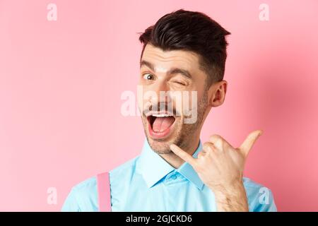 Cheeky and funny guy showing phone gesture, asking to call him and ...