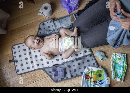 Mother changing a baby diaper Photo: Fotograferna Holmberg / TT / code ...
