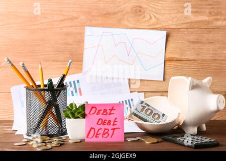 Paper with words DEBT, calculator and coins on wooden background Stock ...