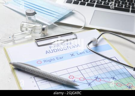 Audiogram, stethoscope, medical mask and laptop on light background ...
