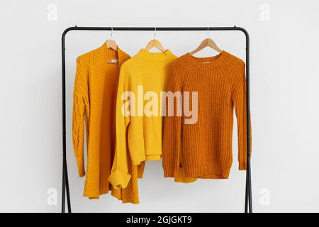 Rack with knitted clothes near light wall, closeup Stock Photo - Alamy