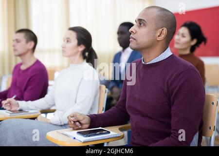 Group of students attentively listening to lecture of female teacher ...