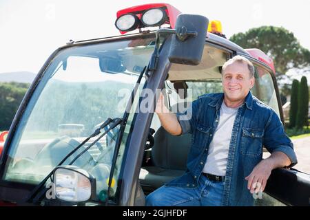 Smiling male farm owner driving tractor Stock Photo - Alamy