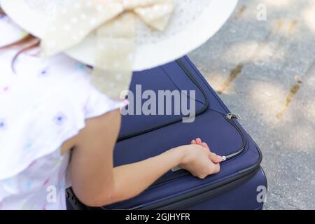 Women's hands open a suitcase with things on a forest road on a summer ...