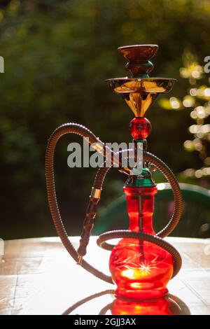 Closeup of glass object with illuminated lit tea candle lamp on table ...