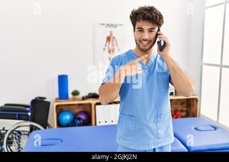 Hispanic physiotherapy man working at pain recovery clinic smiling ...