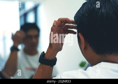 A man is looking in the mirror to preen Stock Photo - Alamy