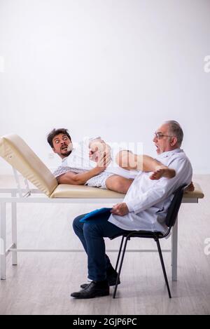 Aggressive old male patient attacking young nurse man with walking ...