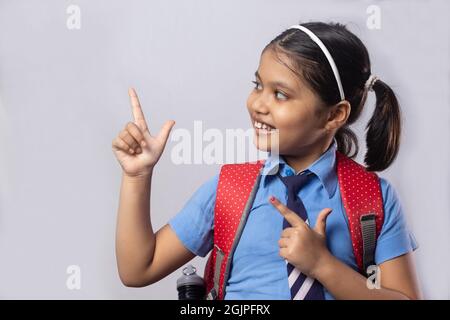 Happy indian school girl pointing advertising isolated on violet ...