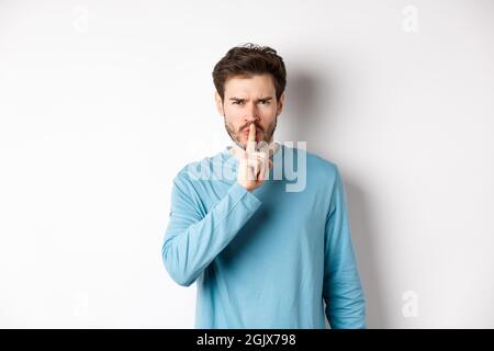 Angry man shushing at camera and telling to be quiet, frowning upset ...