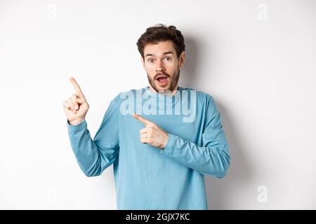 Amazed man showing awesome promo offer, pointing fingers at upper left ...