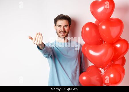 Smiling man beckon you to come closer, follow me gesture, taunting his ...