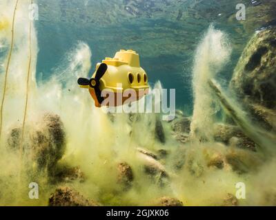 Yellow Duplo submarine diving underwater at cliff with backlight sun ...