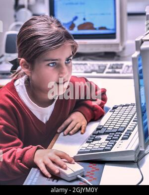 1990s Computer class. Junior blond schoolgirl 7-9 years studying ...