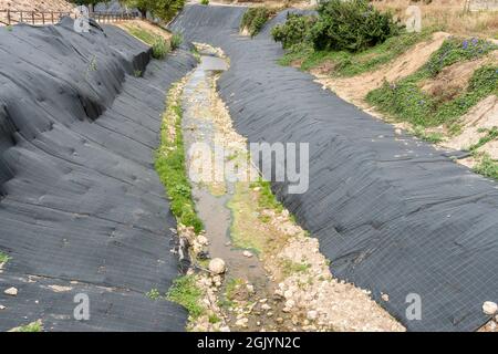 A view of an empty dried canal with an erosion protection system and an ...