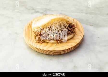 Arepa with shredded beef and cheese on wooden background. Venezuelan ...