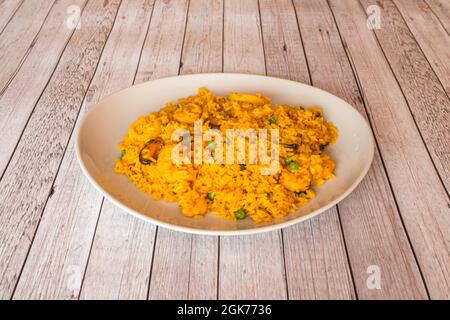Vegetable paella in white plate with beans and slices of onion and ...
