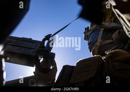 A Marine mans a machine gun mounted on the turret of an LAV-25 light ...