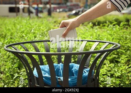 Woman throwing her phone into the garbage bag, posing isolated on gray ...