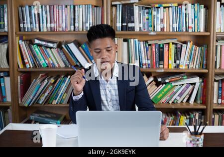 Southeast Asian businessman writing down notes during a meeting at home ...