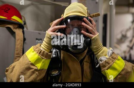 A sailor checks the seal on the mask of his oxygen breathing apparatus ...