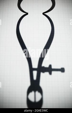 Metal outside spring calipers casting abstract shadow on piece of graph ...