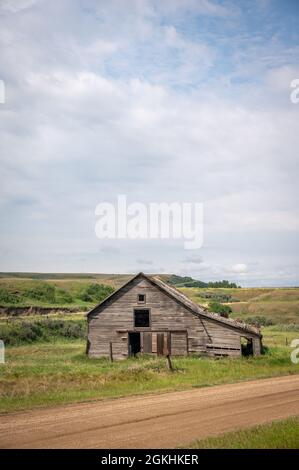 Vertical shot of an old destroyed wooden home on a straw sunny field ...