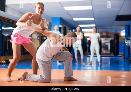 Girl performing hammerlock to male opponent during self defence ...
