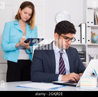 Secretary writing boss instructions Stock Photo - Alamy