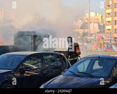 Firefighter extinguishing burning trash containers in yard of house ...