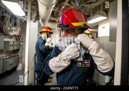 US Navy Seaman dons a helmet prior to firing a .50 caliber machine gun ...