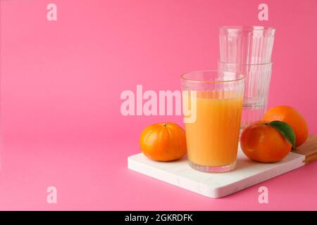 Board with mandarin juice and ingredients on pink background Stock ...